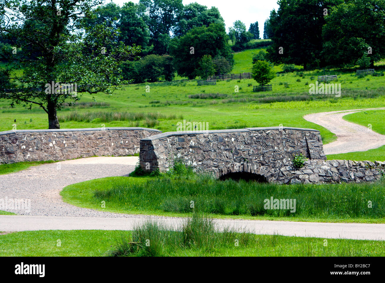 A beautiful winding path over a stone old bridge in the English ...