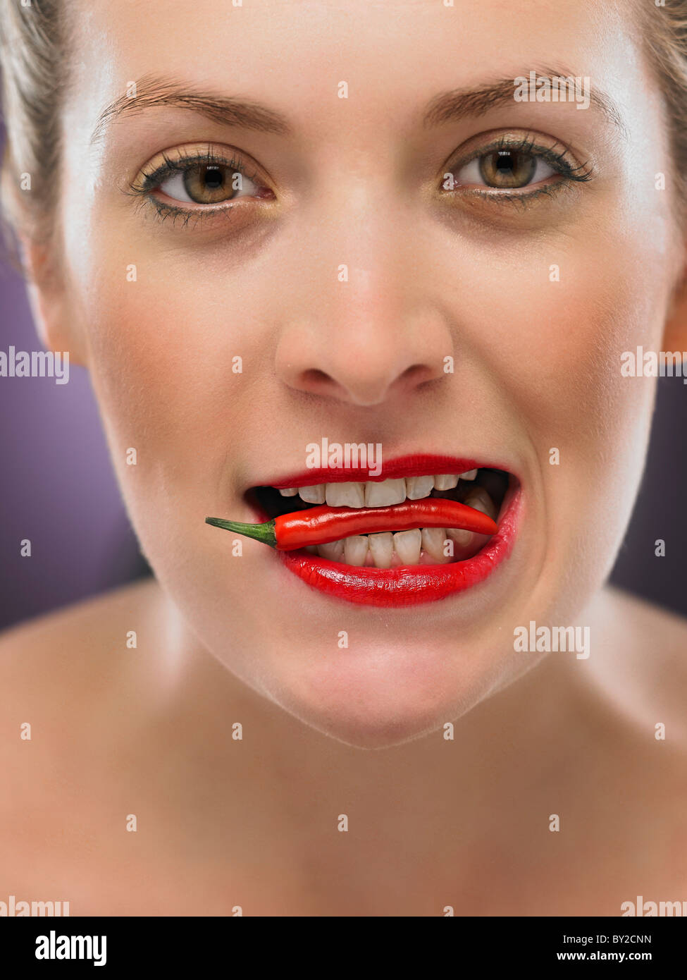 white blonde woman biting a chili pepper Stock Photo - Alamy