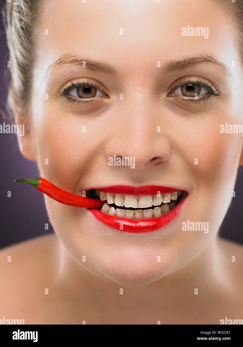 white blonde woman biting a chili pepper Stock Photo - Alamy