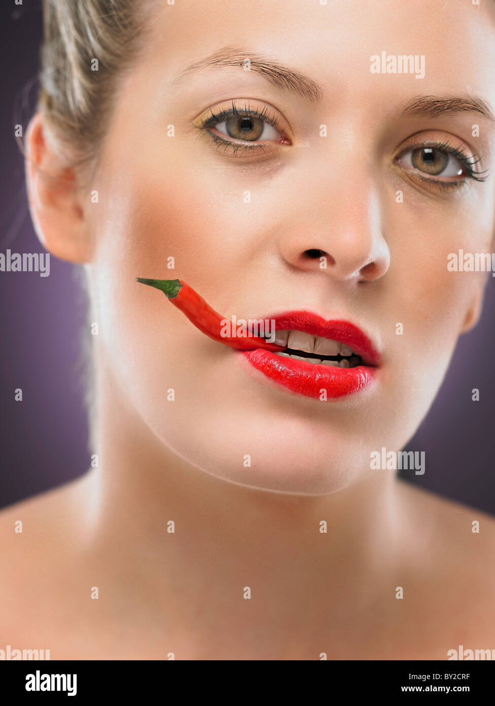 white blonde woman biting a chili pepper Stock Photo - Alamy