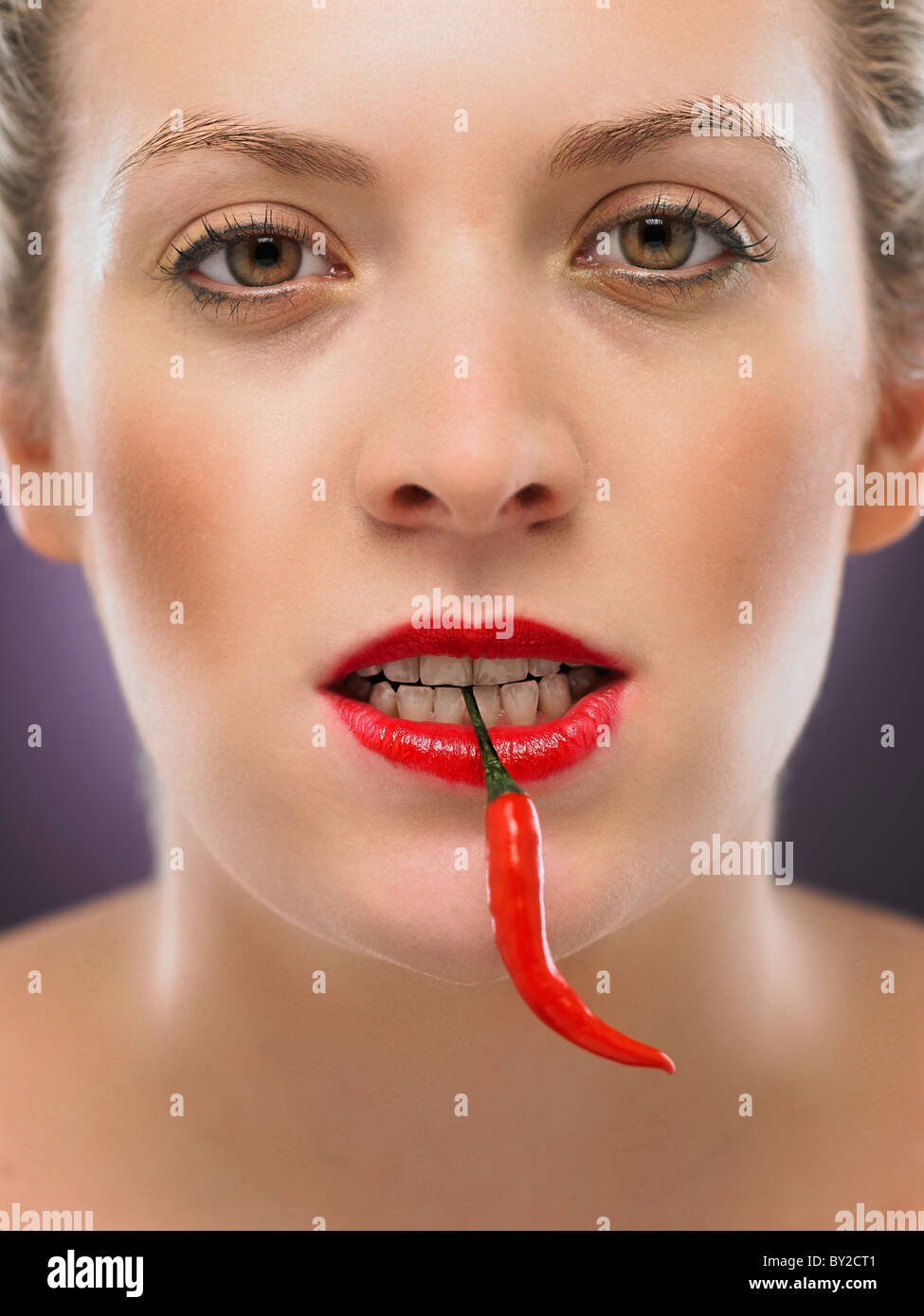 white blonde woman biting a chili pepper Stock Photo - Alamy
