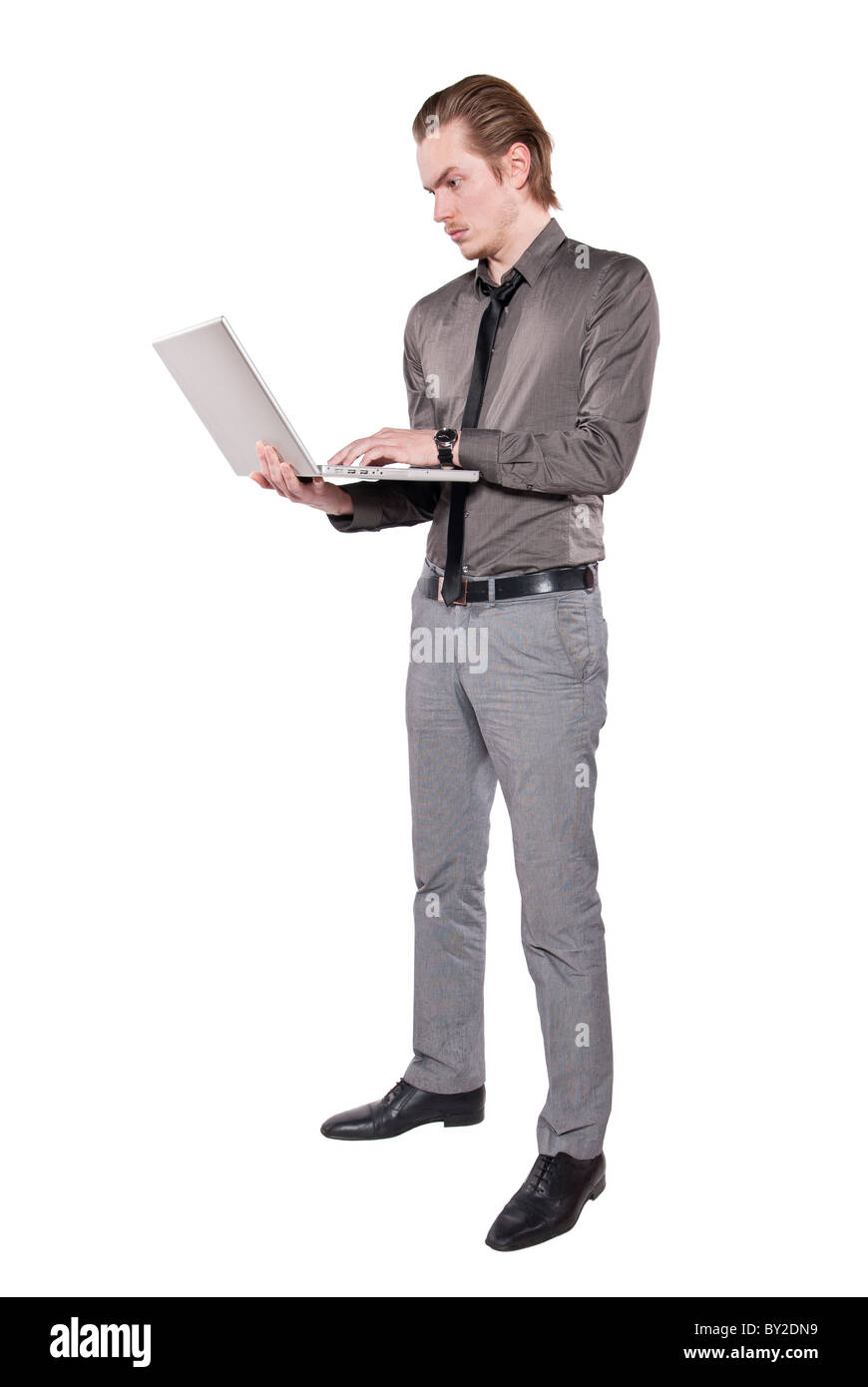 A young man stands with a computer. Studio photo on white background ...