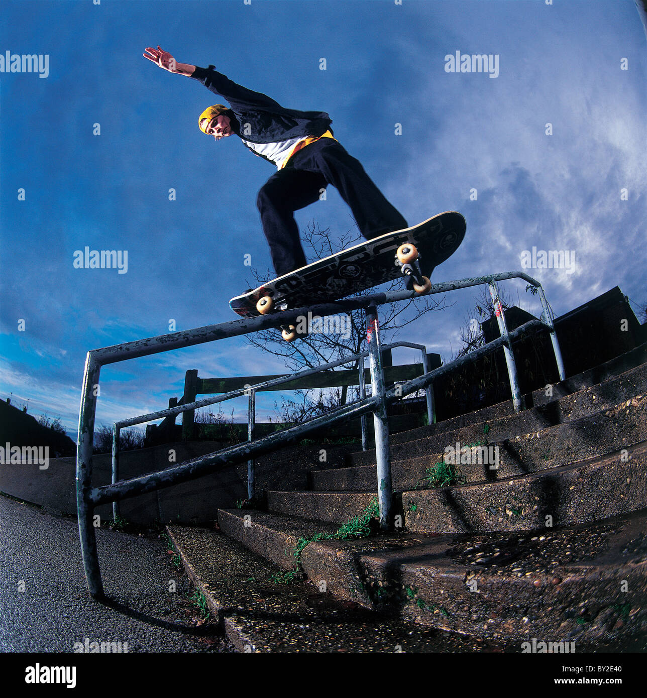 Skateboarder performs trick on a handrail Stock Photo - Alamy