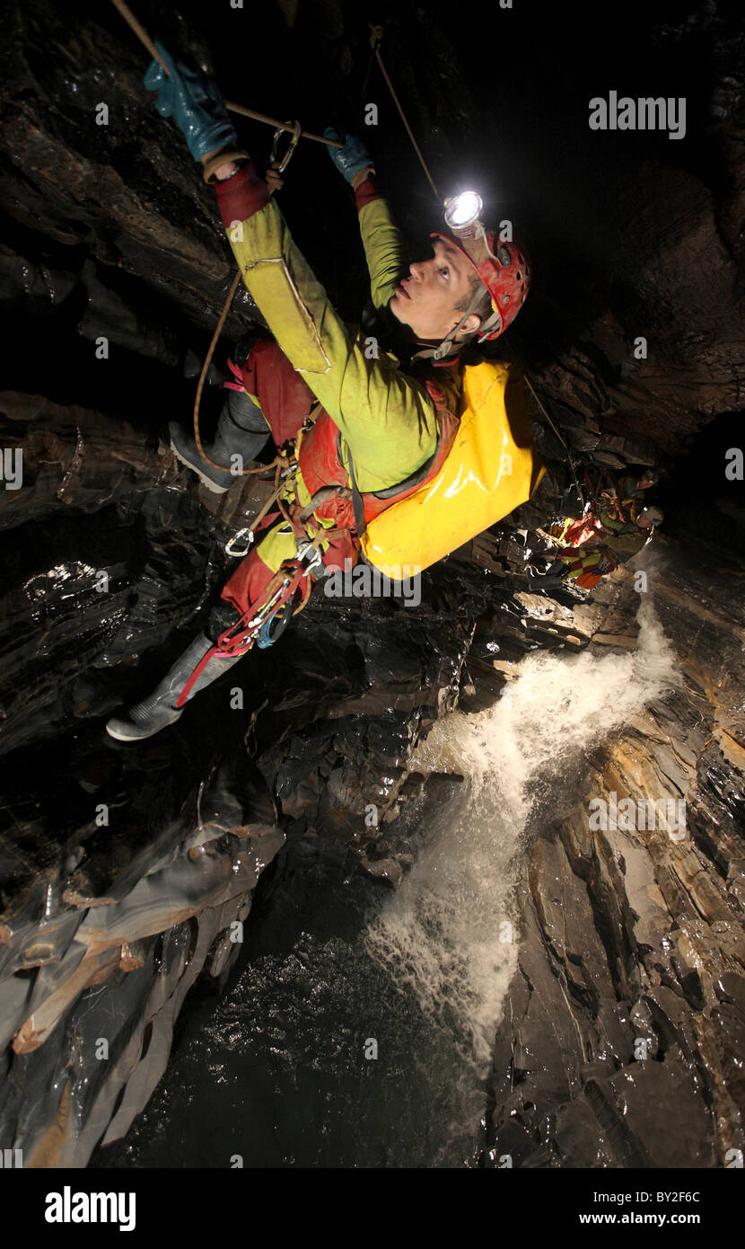 A young man holds onto a rope above a river in a cave in China Stock ...