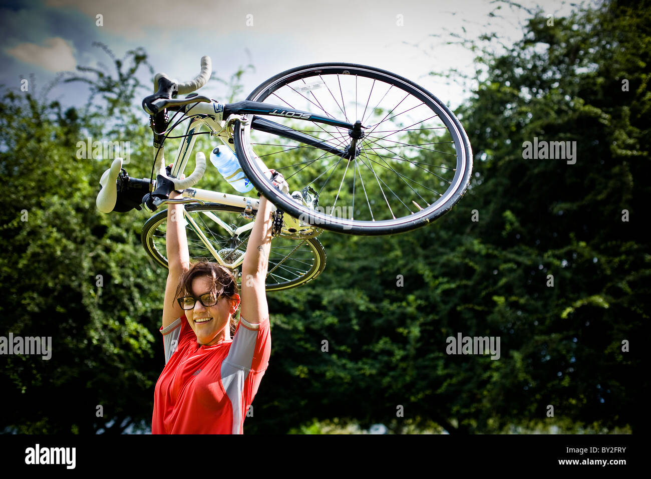 Holding her bike above her head, a young female fixed gear bicycle ...