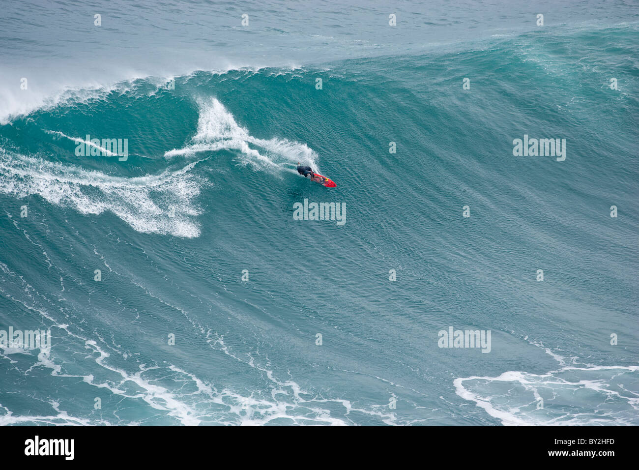 A young man tow surfing into a huge wave, on the north shore of Oahu ...