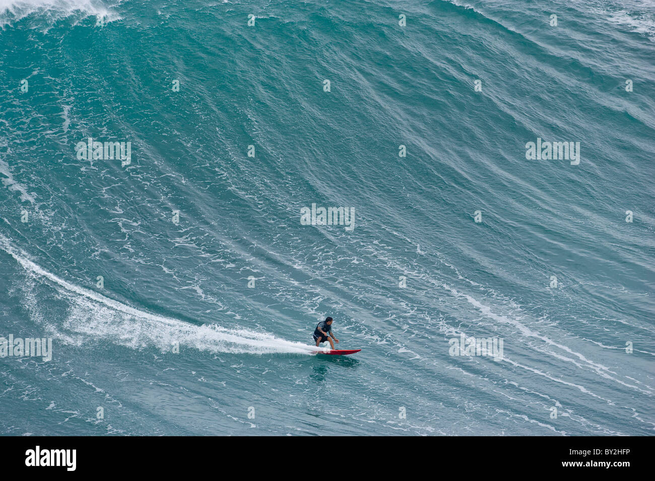 A young man tow surfing into a huge wave, on the north shore of Oahu ...