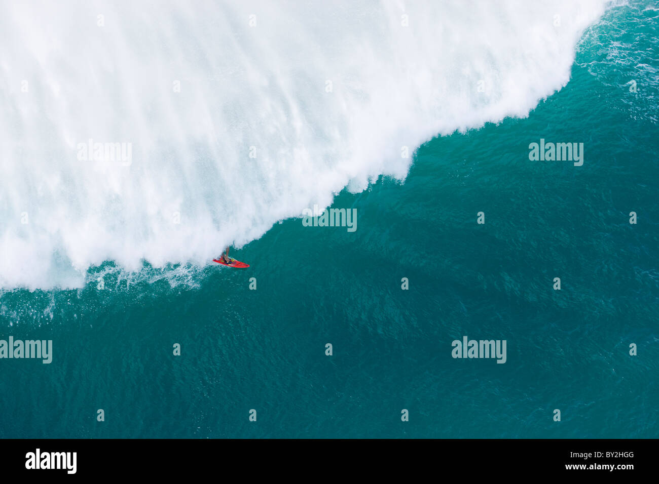 A young man tow surfing into a huge wave, on the north shore of Oahu ...