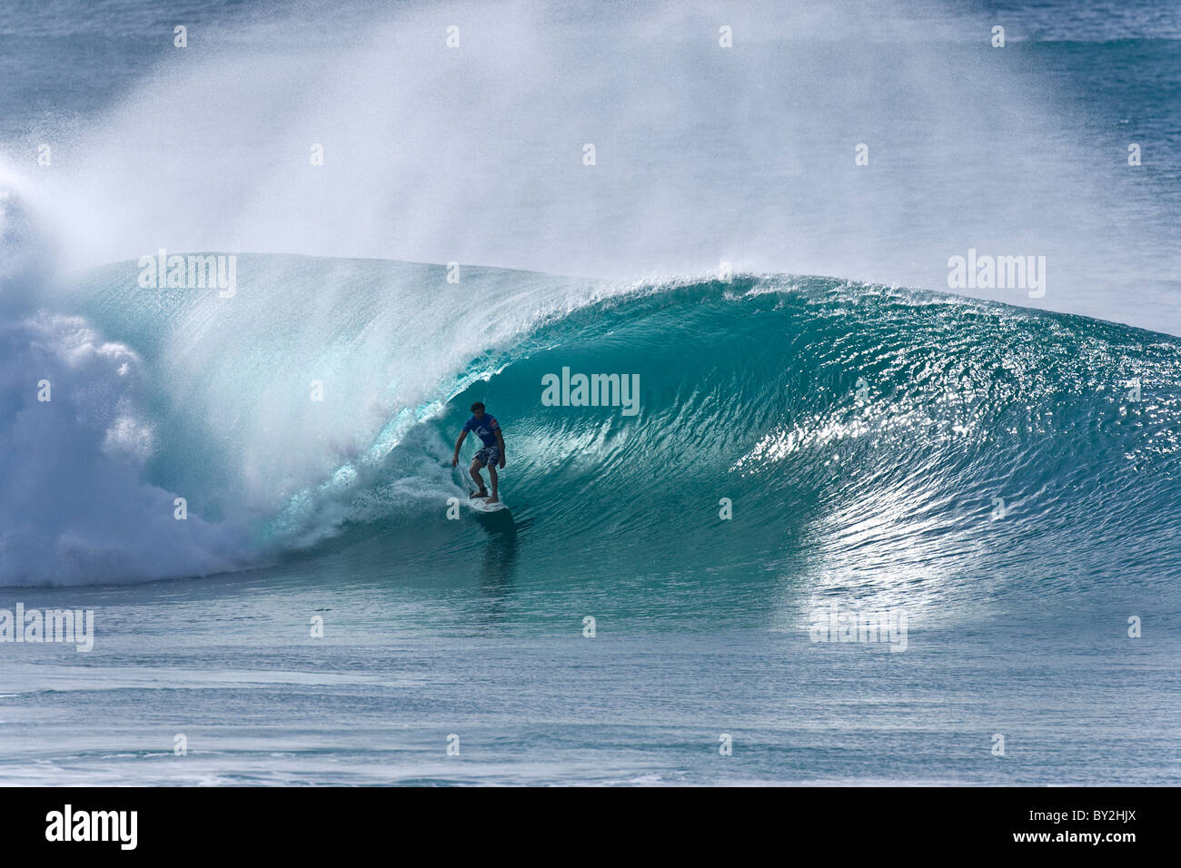 A young man surfs a perfect big barreling wave at the Pipeline, on th ...