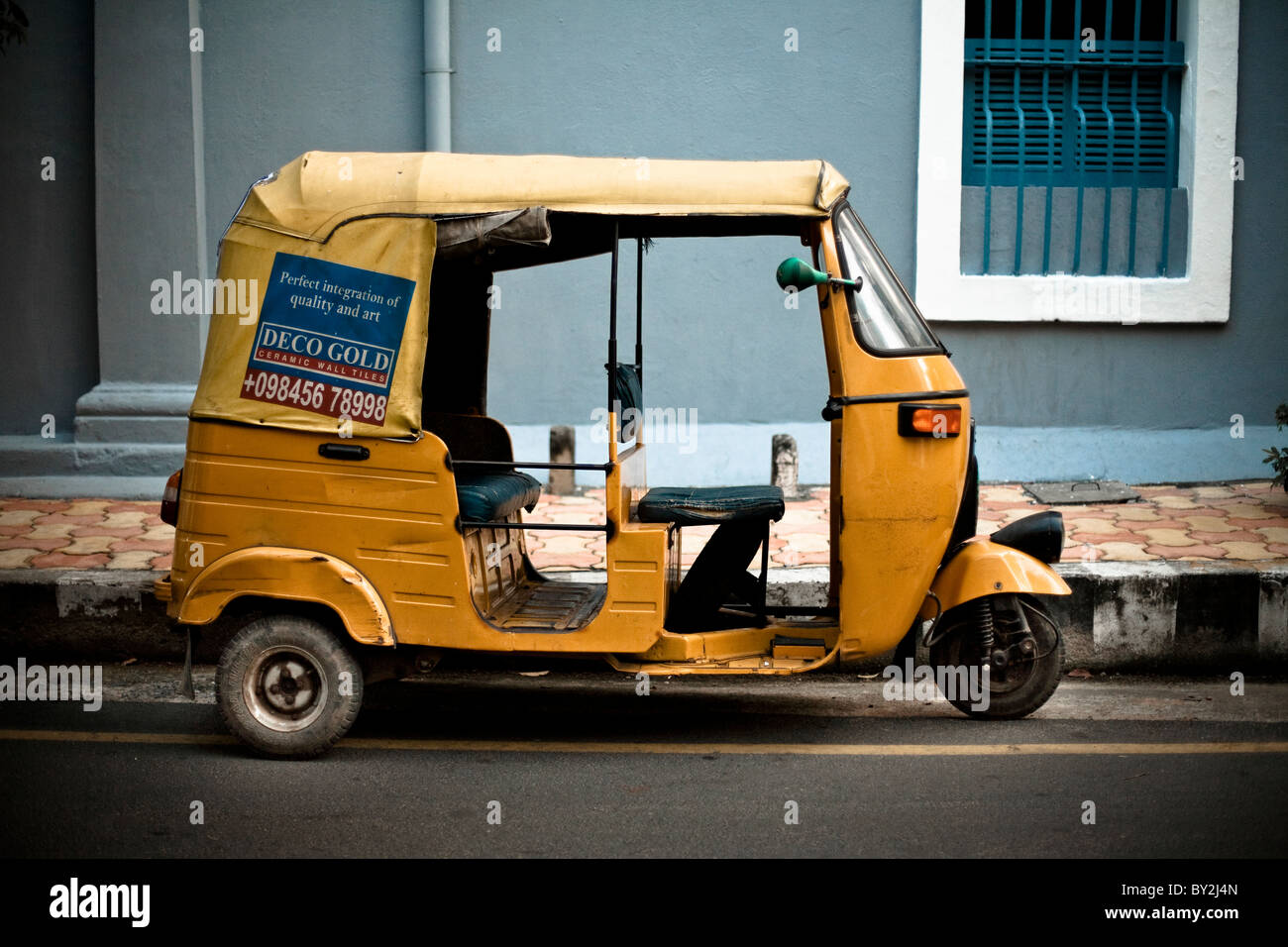 A yellow rickshaw against a blue wall Stock Photo - Alamy