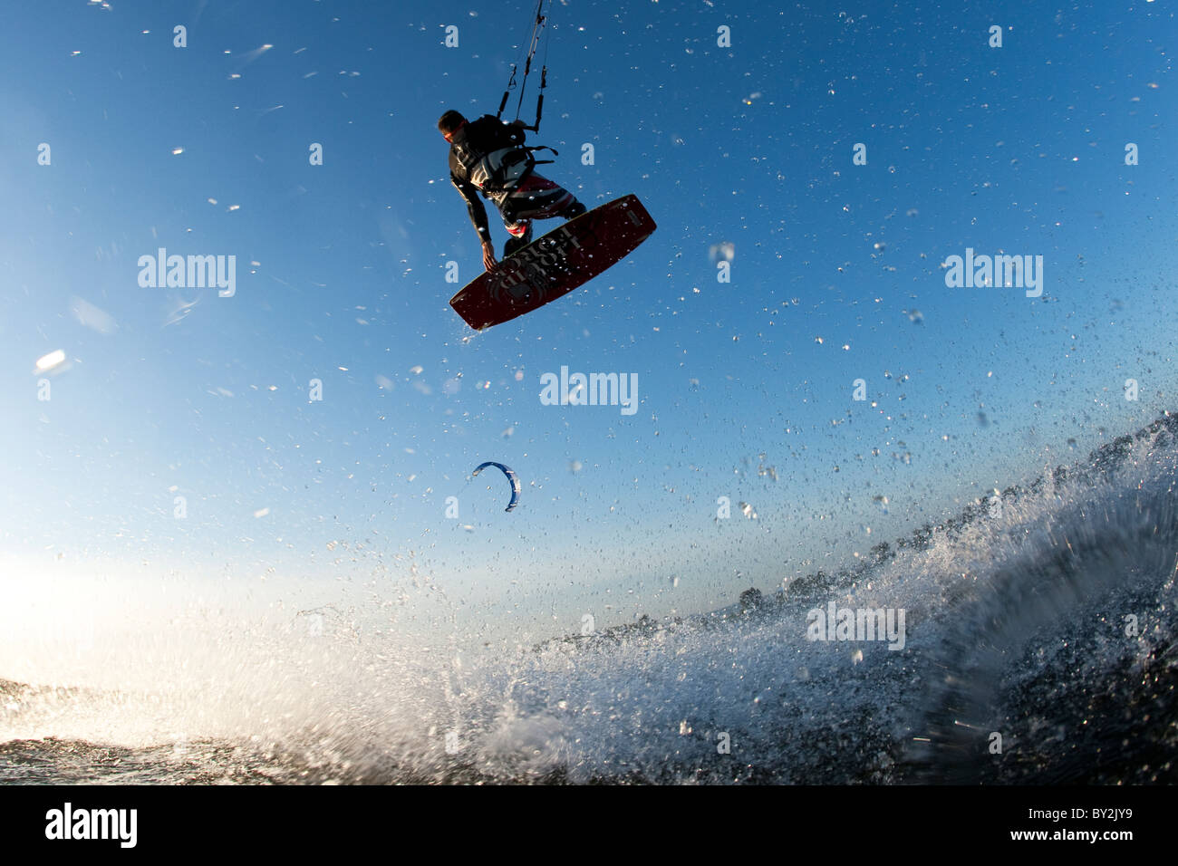 Low angle perspective of a kiteboarder jumping into the air and ...