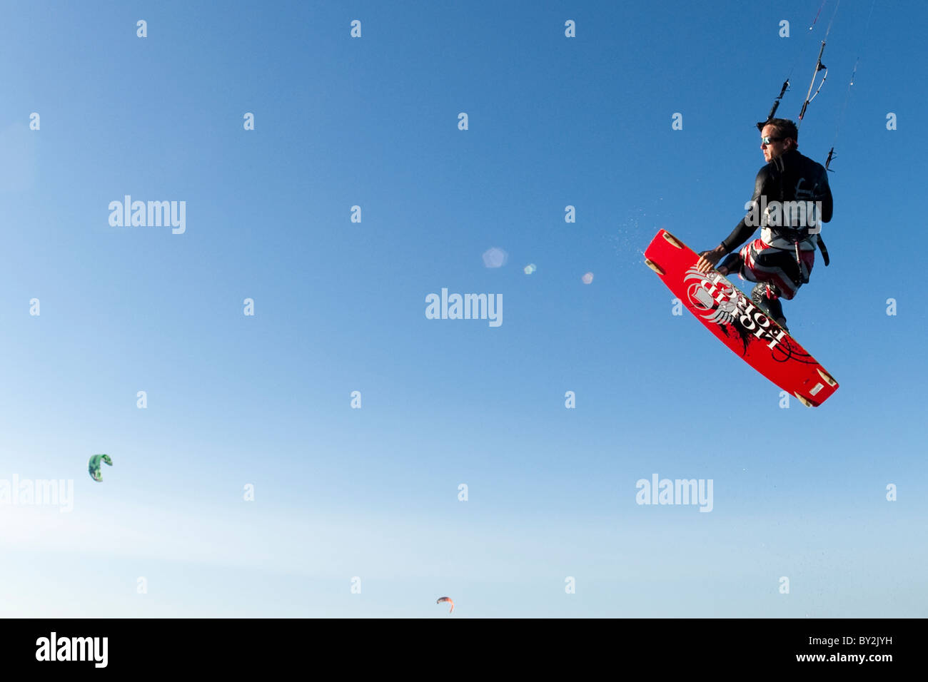 Low angle perspective of a kiteboarder jumping high into the air with ...
