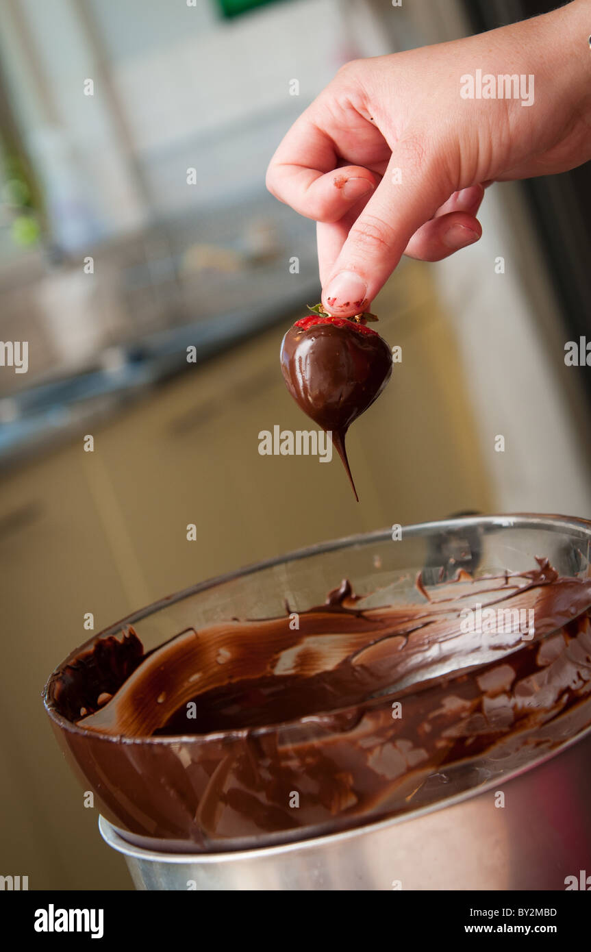 Handing dipping strawberry in chocolate Stock Photo - Alamy
