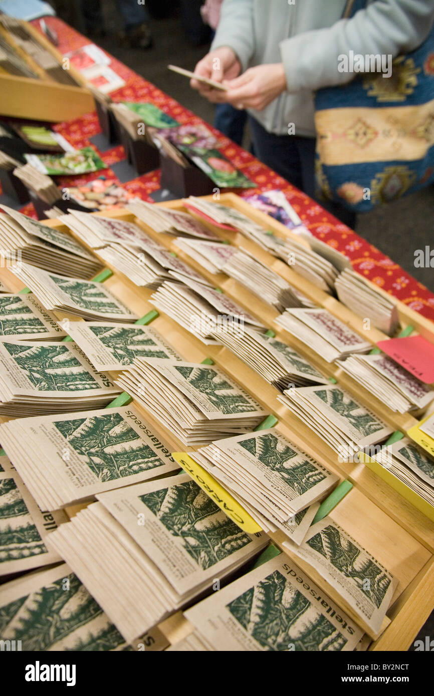 A woman examines a packet of organic seeds in front of a display at the ...