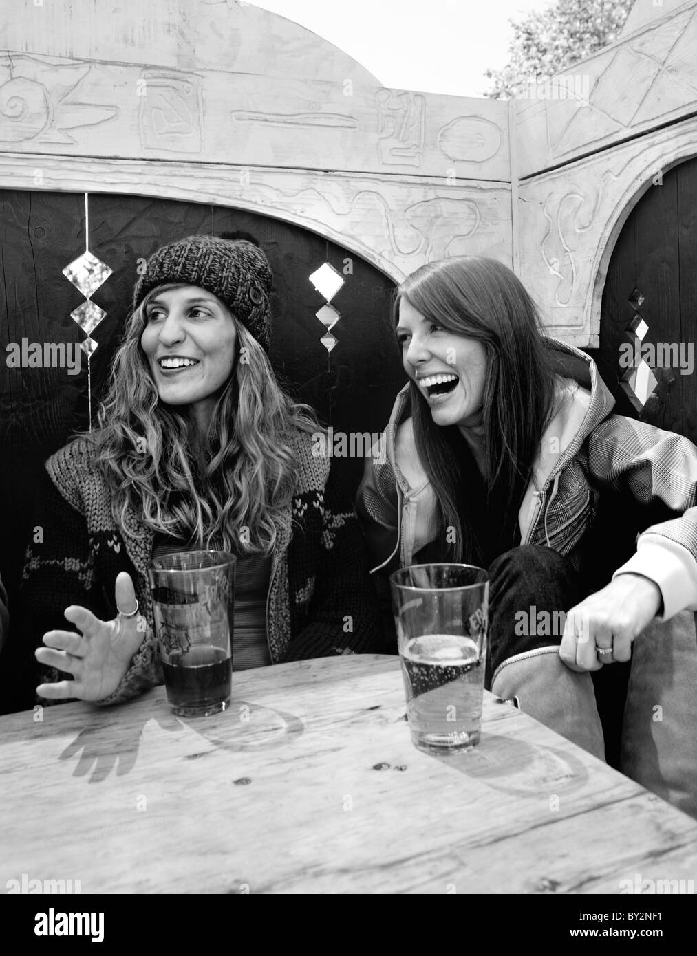 Two women laugh while drinking beers Stock Photo - Alamy