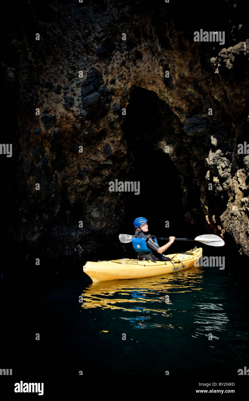 A woman paddles her kayak into a sea cave on Santa Cruz Island in the ...