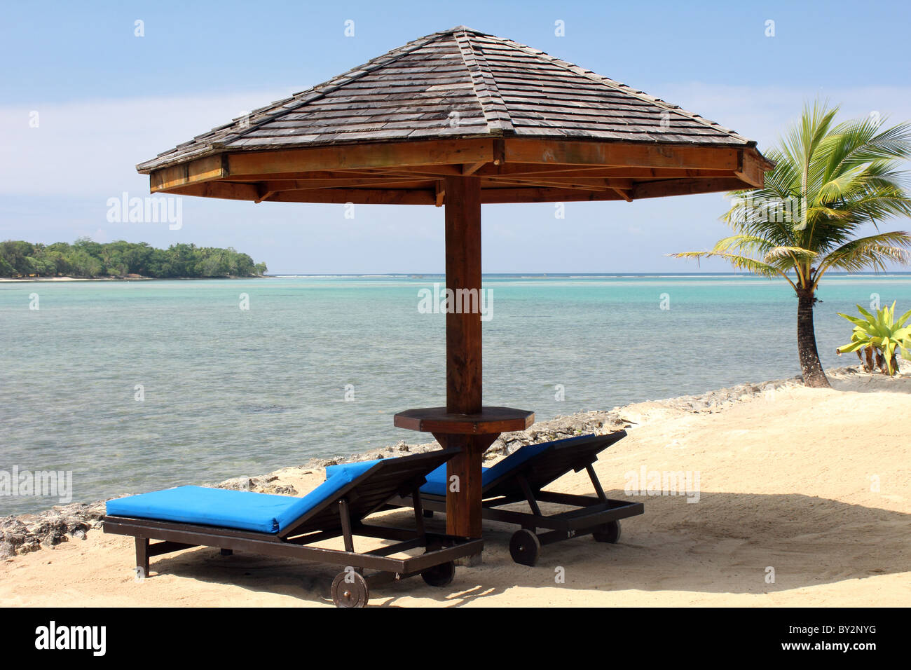 THATCH UMBRELLA AND LOUNGES ON TROPICAL ISLAND BLUE SKY BACKGROUND BDA ...