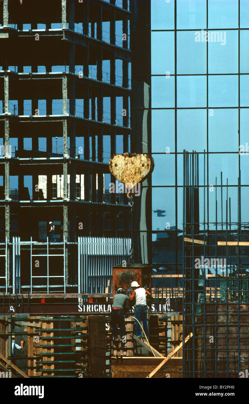Two men securing equipment being lowered by crane at commercial ...