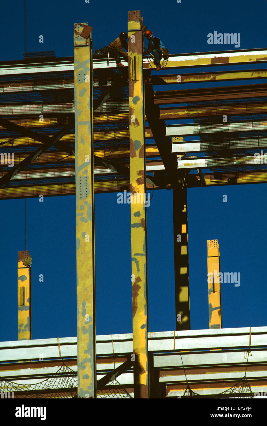 Two construction workers on steel beams at commercial construction site ...