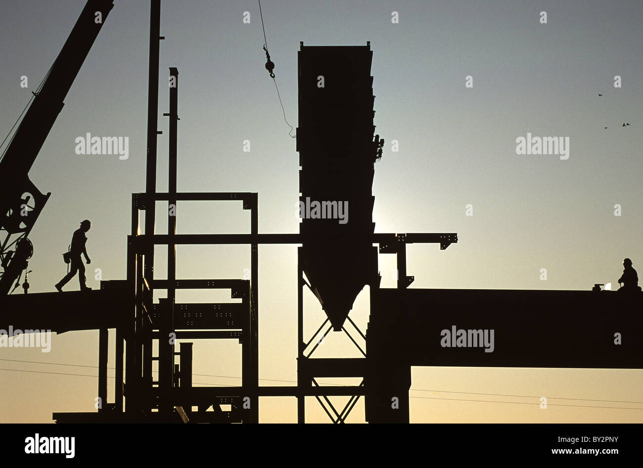 Silhouette of workers on beams of copper processing plant under ...