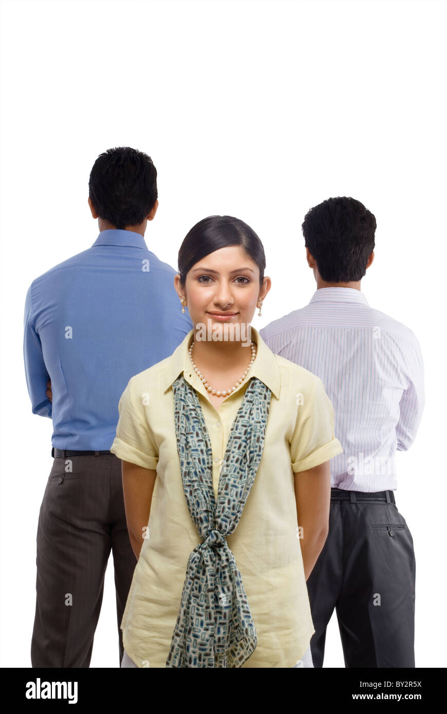 One businesswoman facing the camera and two businessmen facing away ...