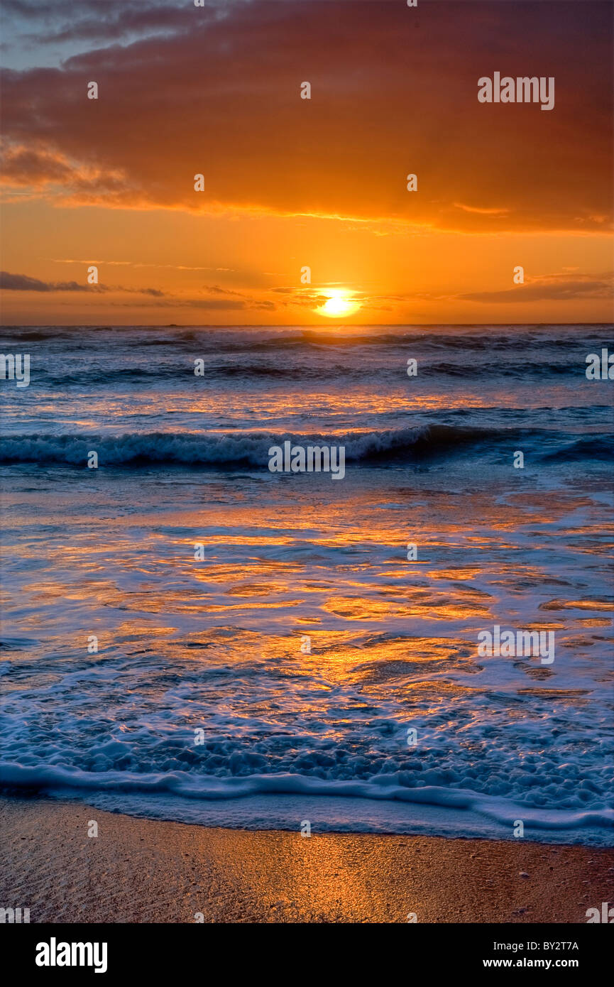 Sun setting over breaking waves Stock Photo - Alamy