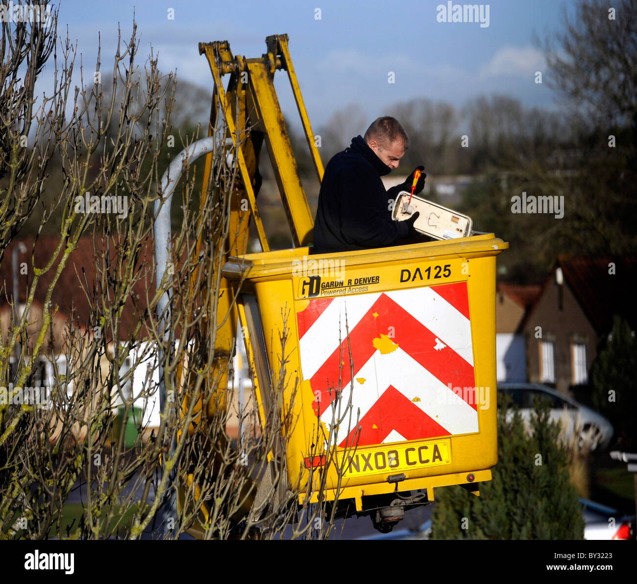 A council workman uses a cherry picker one man lifting hoist to repair ...