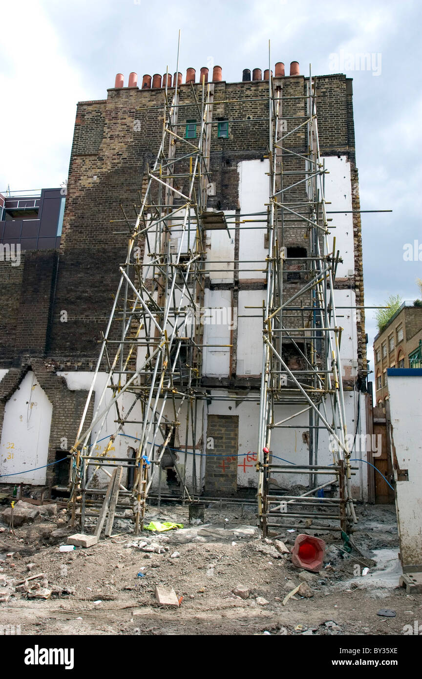 Scaffolding poles supporting the side of semi-demolished building Stock ...