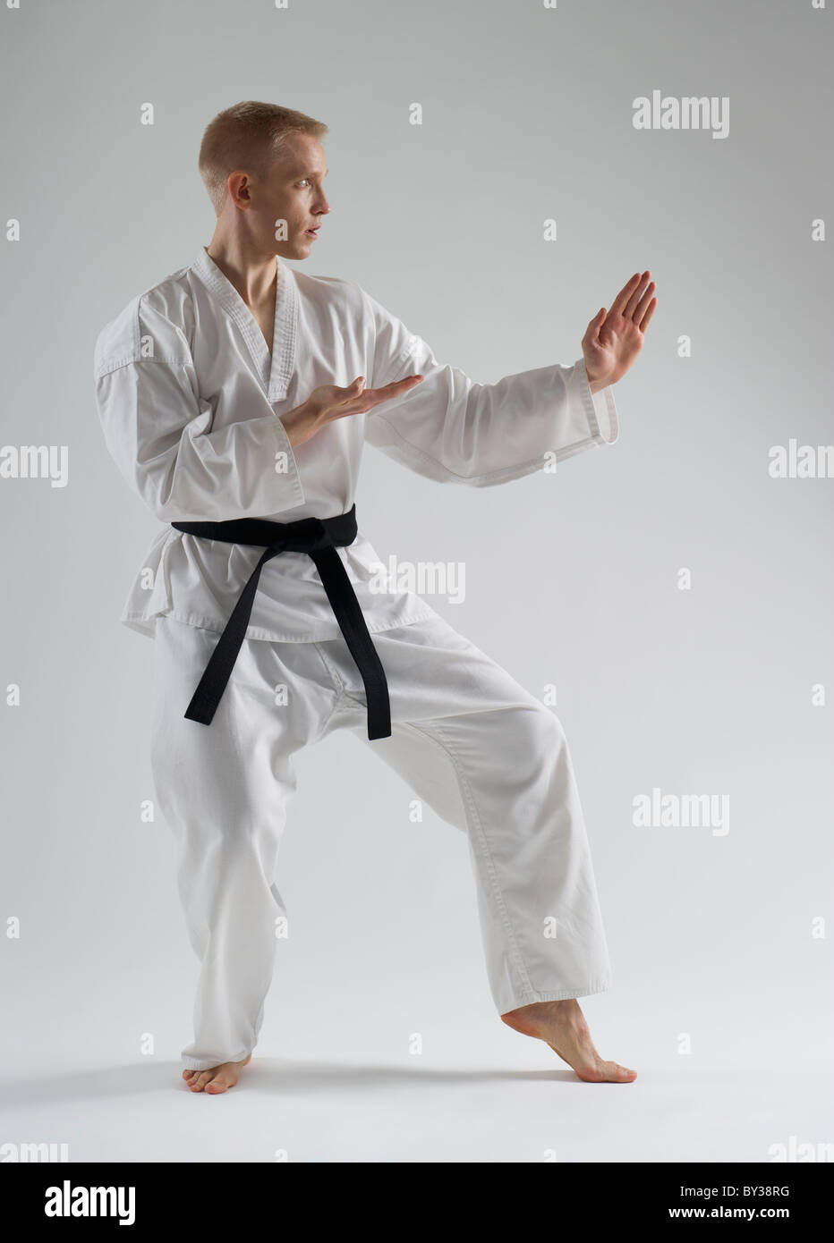 Young man performing karate stance on white background Stock Photo - Alamy
