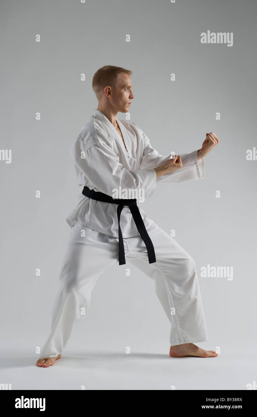 Young man performing karate stance on white background Stock Photo - Alamy