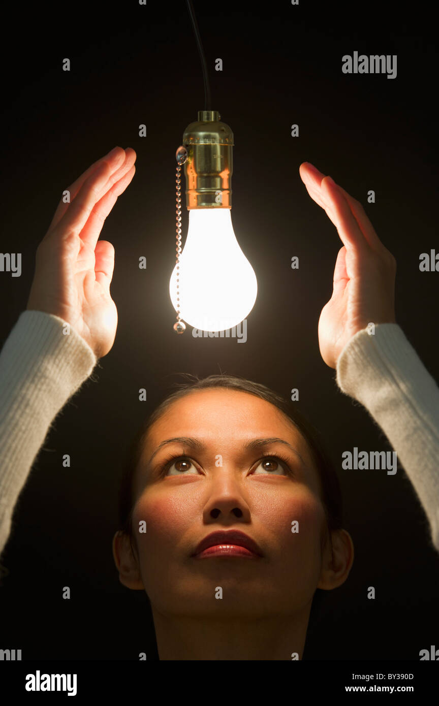 Woman looking up at illuminated lightbulb Stock Photo - Alamy