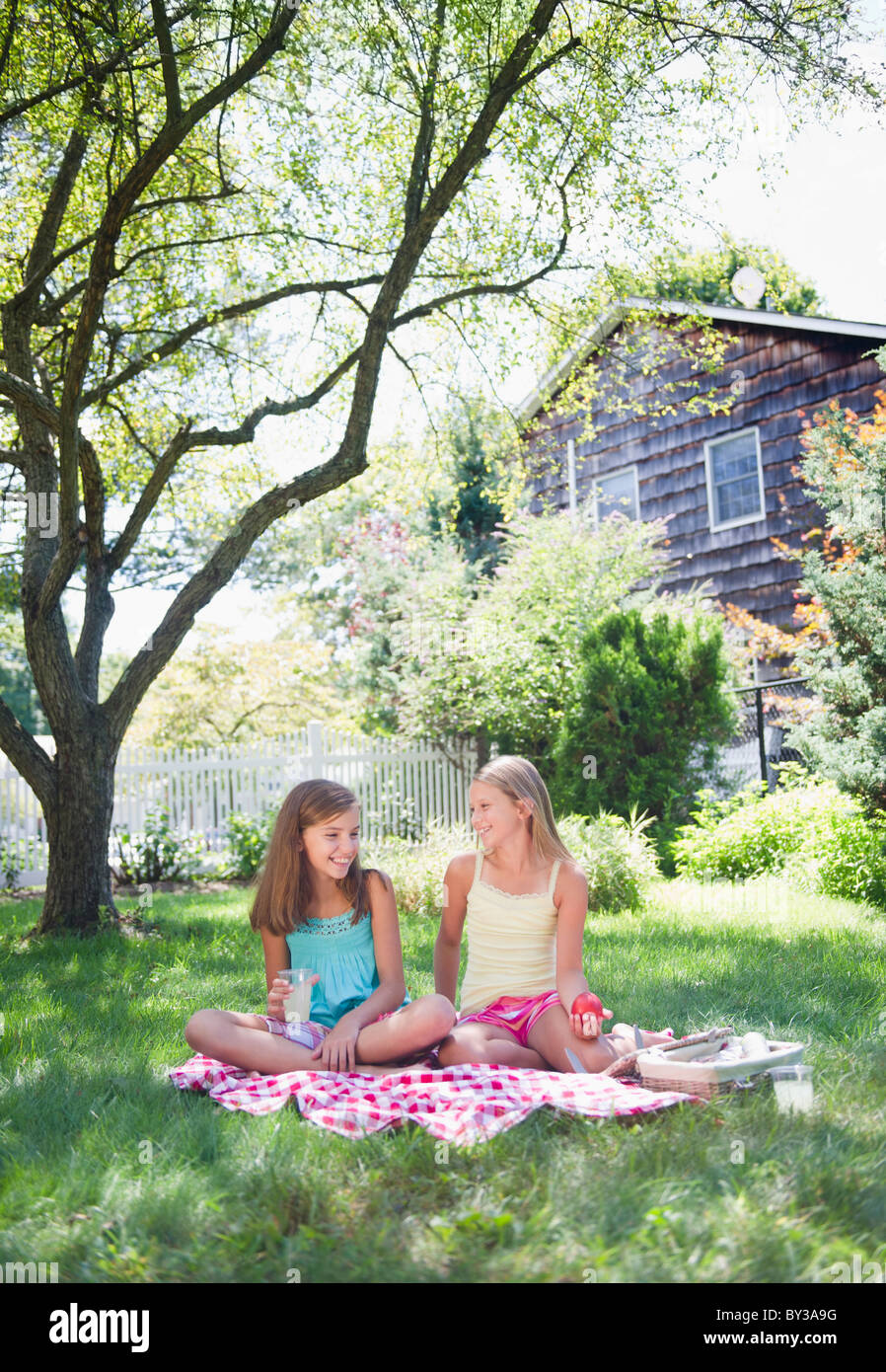 USA, New York, Two girls (10-11, 10-11) sitting on blanket in backyard ... USA, New York, Two girls (10-11, 10-11) sitting on blanket in backyard ...