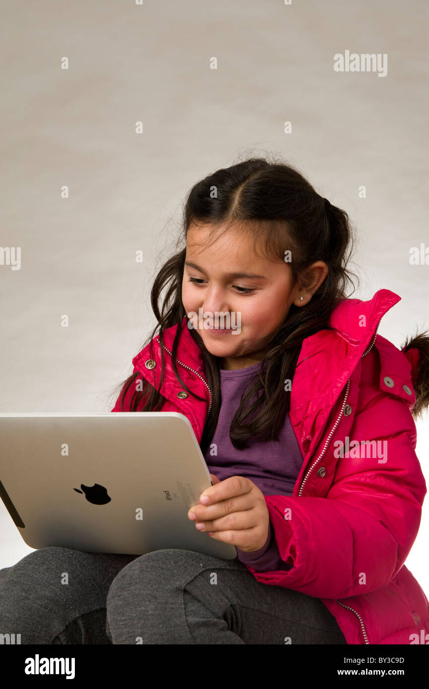Studio shot of a young girl wearing a red coat and playing a game on ...