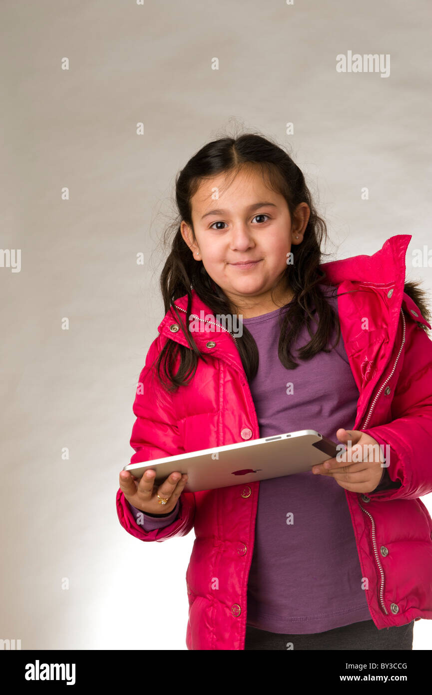 Studio shot of a young girl wearing a red coat and playing a game on ...