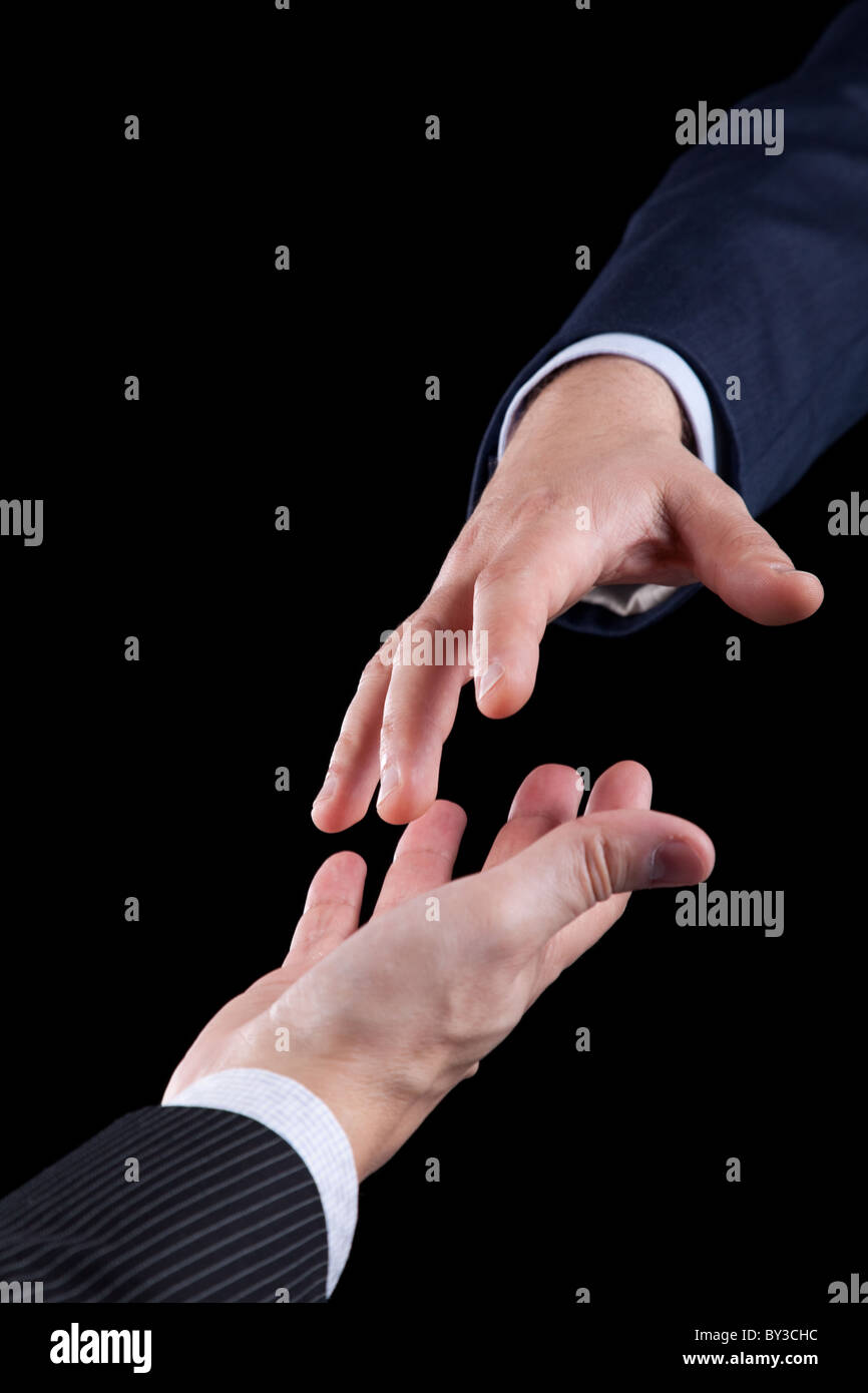 Businessman giving his hand to help another men (isolated on black ...