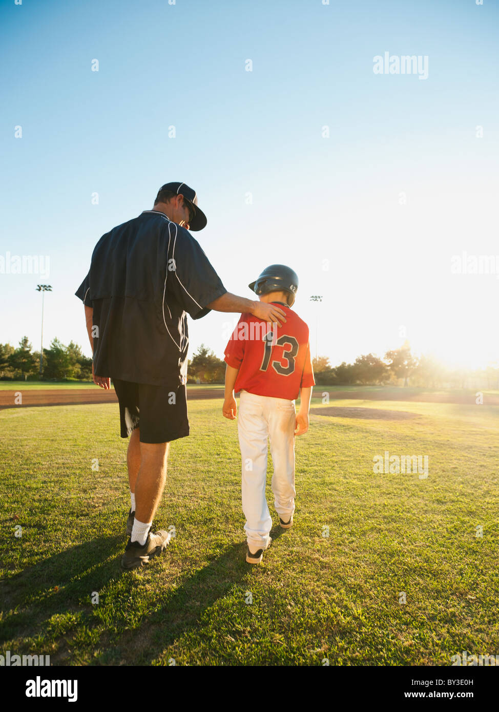 USA, California, Ladera Ranch, man and boy (10-11) walking on baseball ...