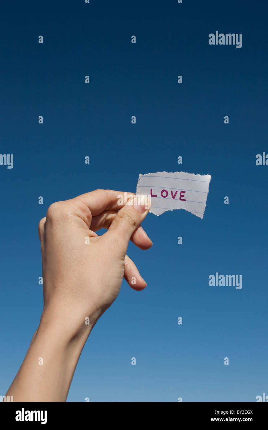 USA, Arizona, Winslow, Human hand holding love note against blue sky ...