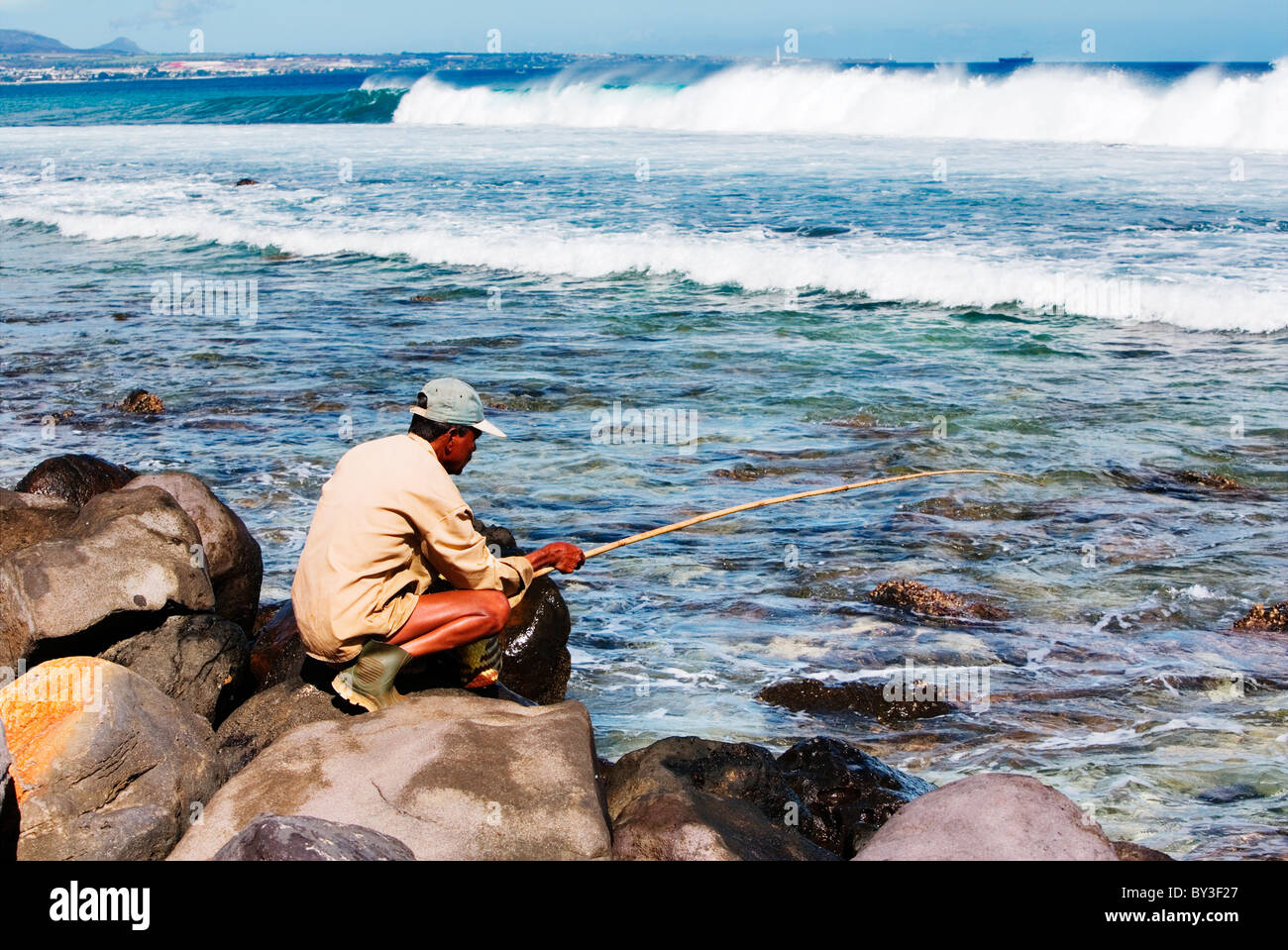 Mauritian man fishing from rocks. Big waves, Balaclava, Mauritius Stock ...