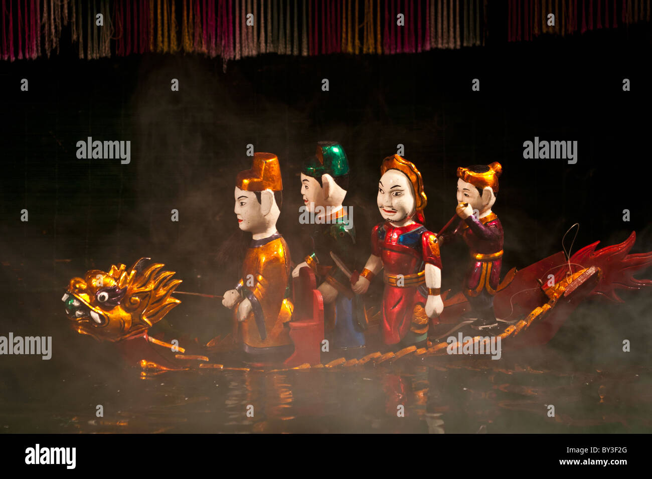 Puppets riding in a dragon boat through firework smoke at the Than Long ...