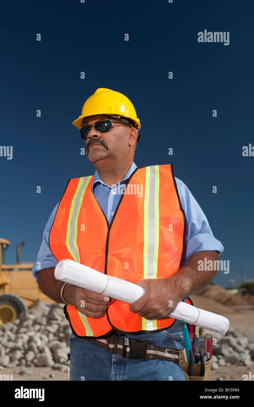Construction worker holding blueprint on building site Stock Photo - Alamy