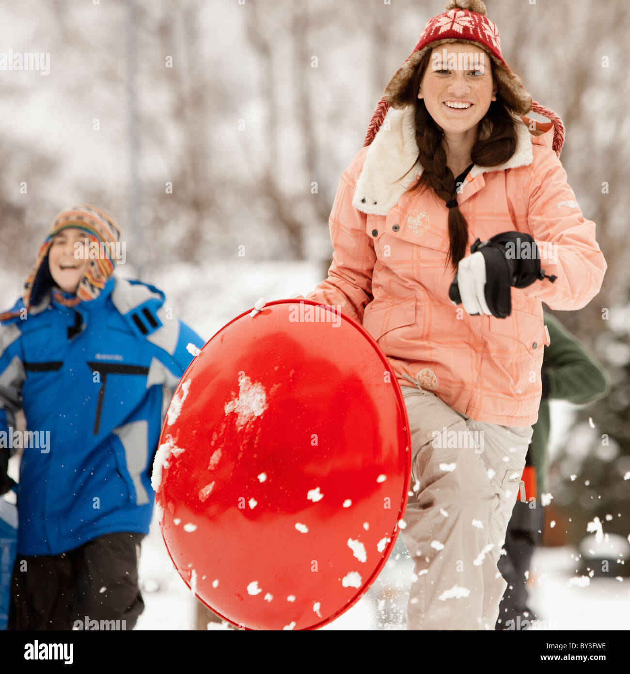 USA, Utah, Provo, Teenage (16-17) girl running with sledge, boys and ...