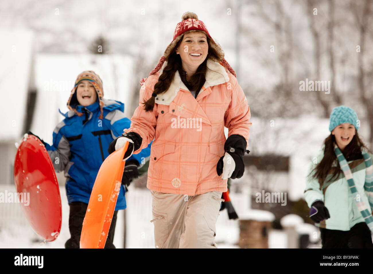 USA, Utah, Provo, Teenage (16-17) girl running with sledge, boys and ...