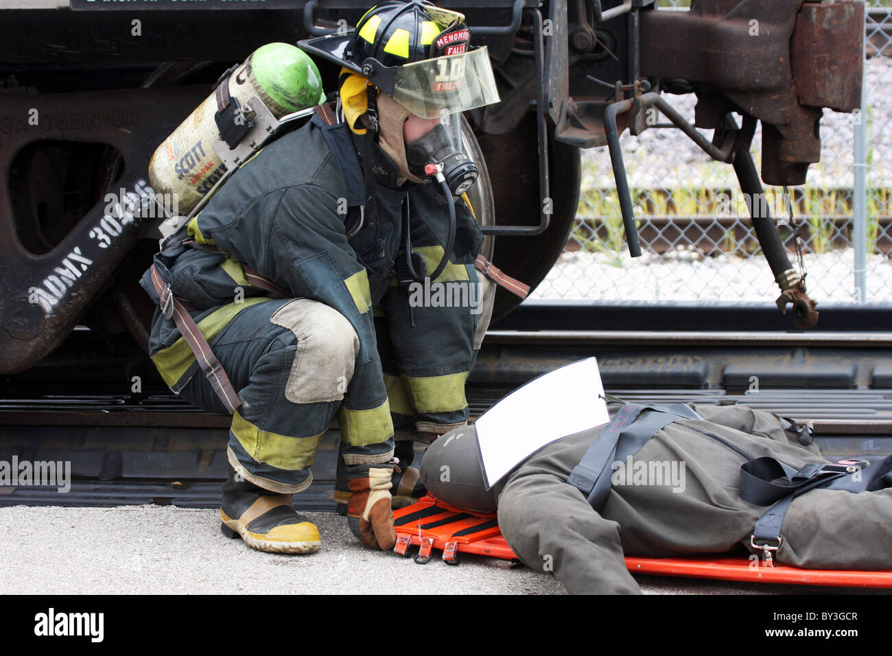 A firefighter beginning to lift a training dummy at a haz mat exercise ...