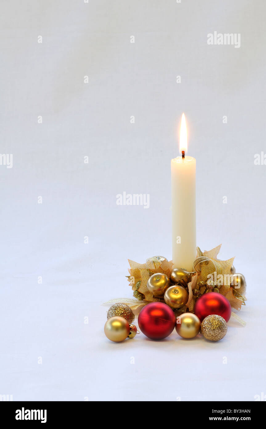 Christmas candle and red and gold baubles in vertical format with a ...