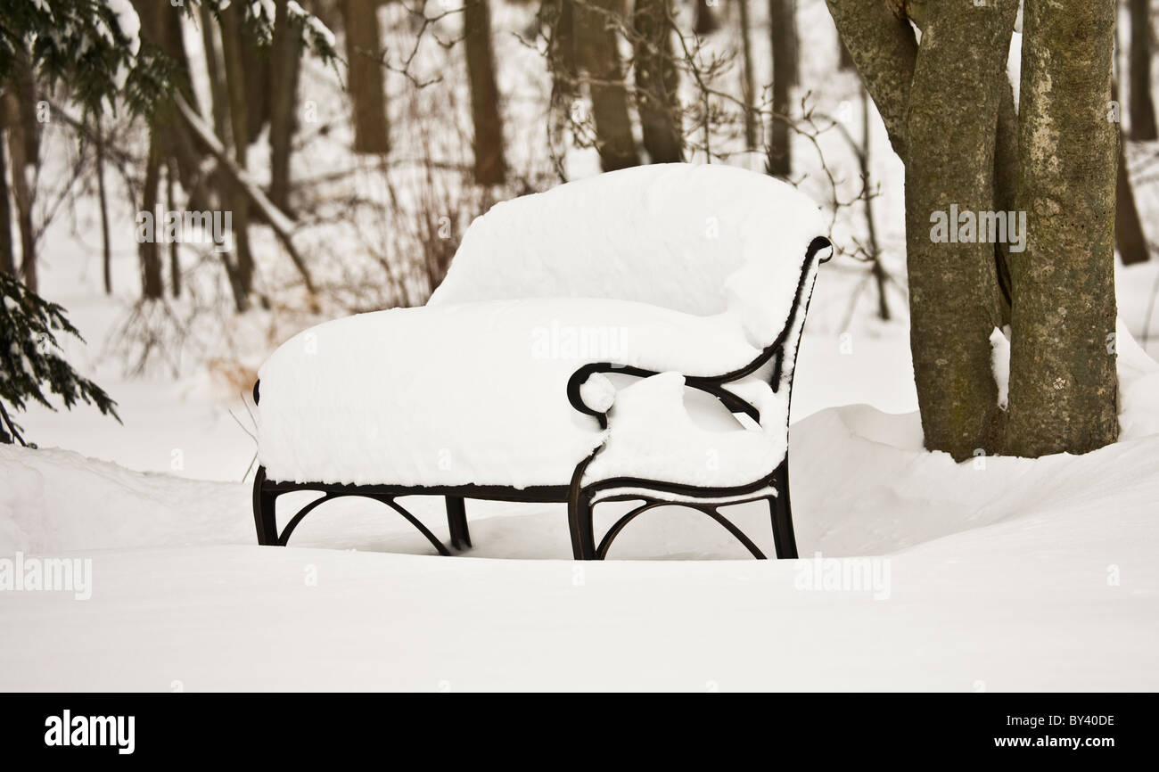 Winter snow storm scene, deep snow covered garden bench seat close up ...