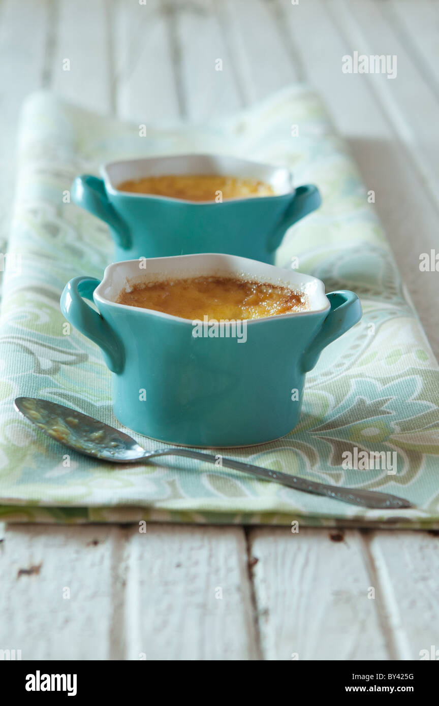 Creme brulee in blue ramekins on a rustic white surface Stock Photo - Alamy