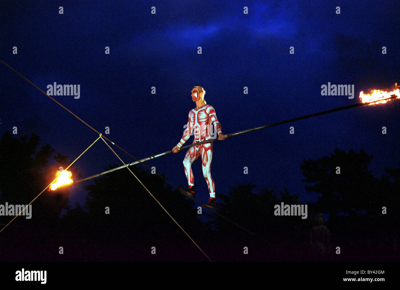 A tight rope walker uses a balancing pole with fire at each end Stock ...