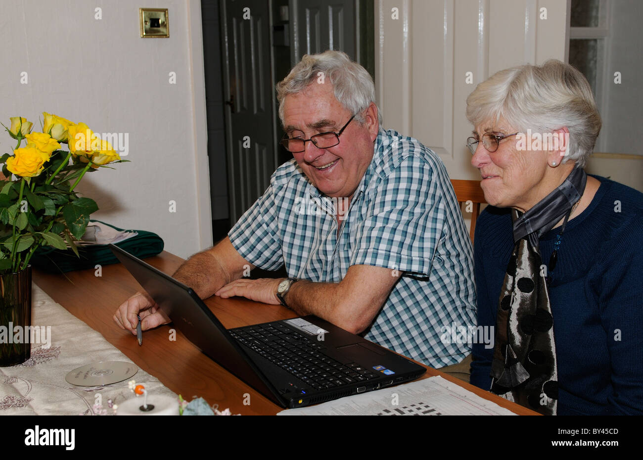 Elderly couple use their laptop to Skype friends over the Internet from ...