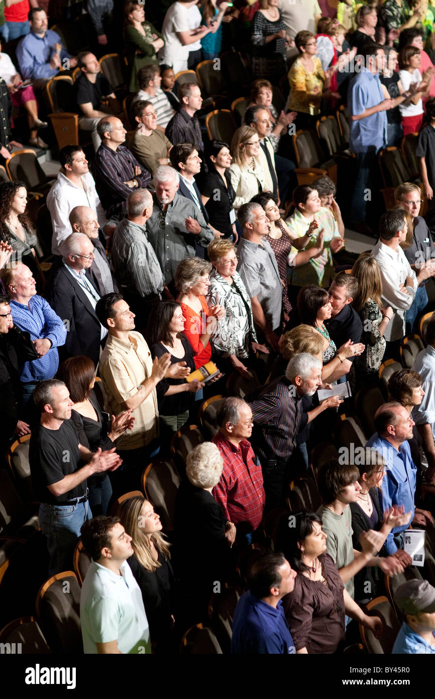 Crowd of fans at rock 'n roll concert stand in front of their seats as ...
