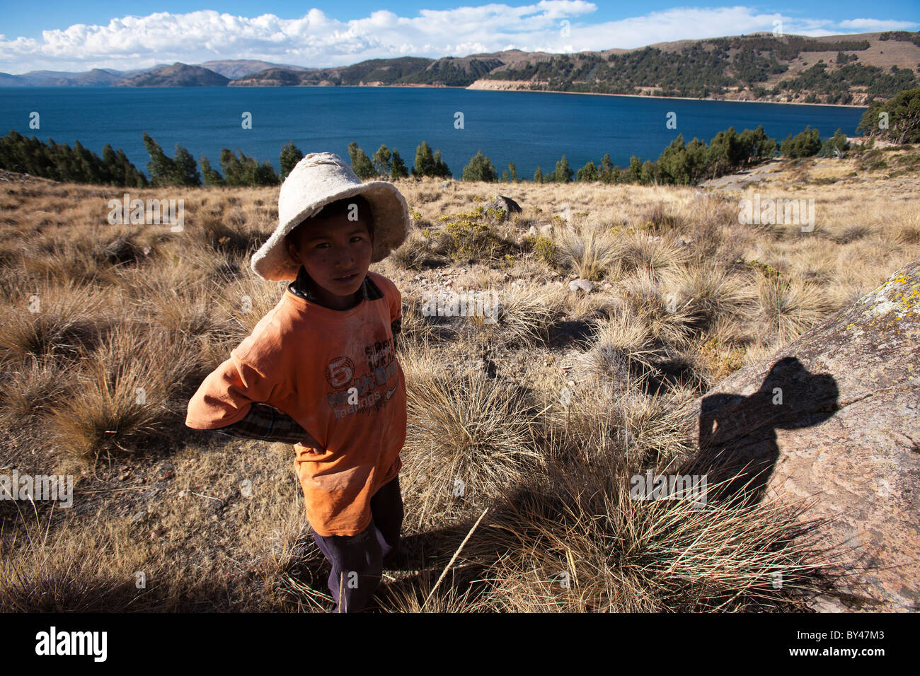 A young Peruvian farm boy on the island of Suasi with lake Titicaca in ...